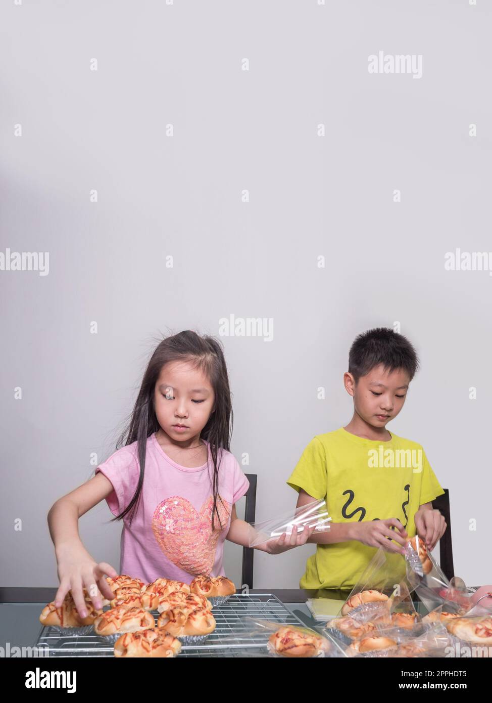 Adorable kid girl and boy separate packing baked pork sausage with ...