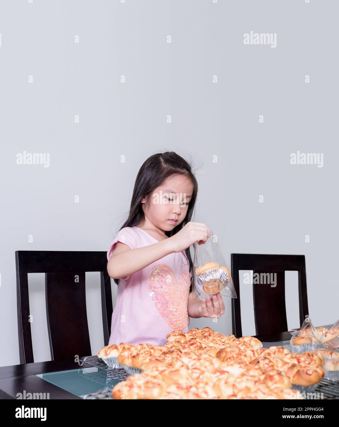 Adorable kid girl separate packing baked pork sausage with mayonnaise ...