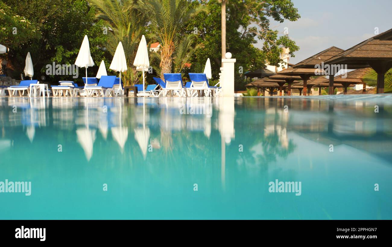 Empty sunbeds and closed parasols on morning, by the hotel pool ...