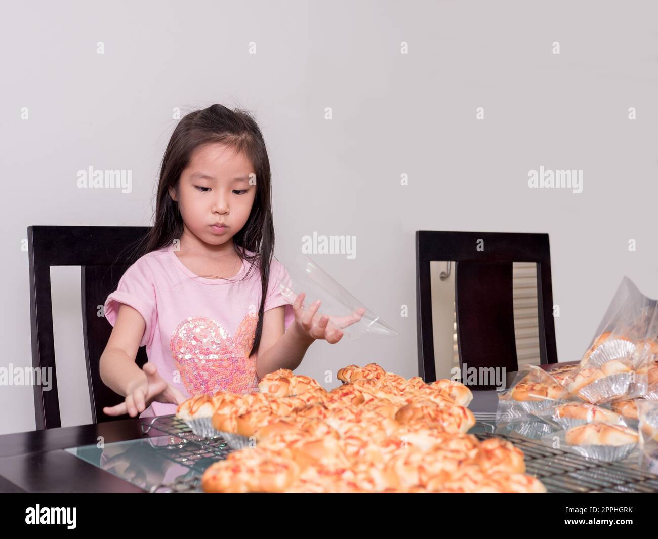Adorable kid girl separate packing baked pork sausage with mayonnaise ...