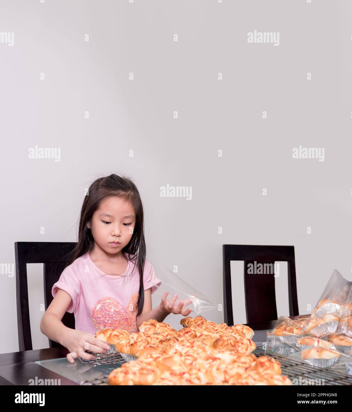 Adorable kid girl separate packing baked pork sausage with mayonnaise ...