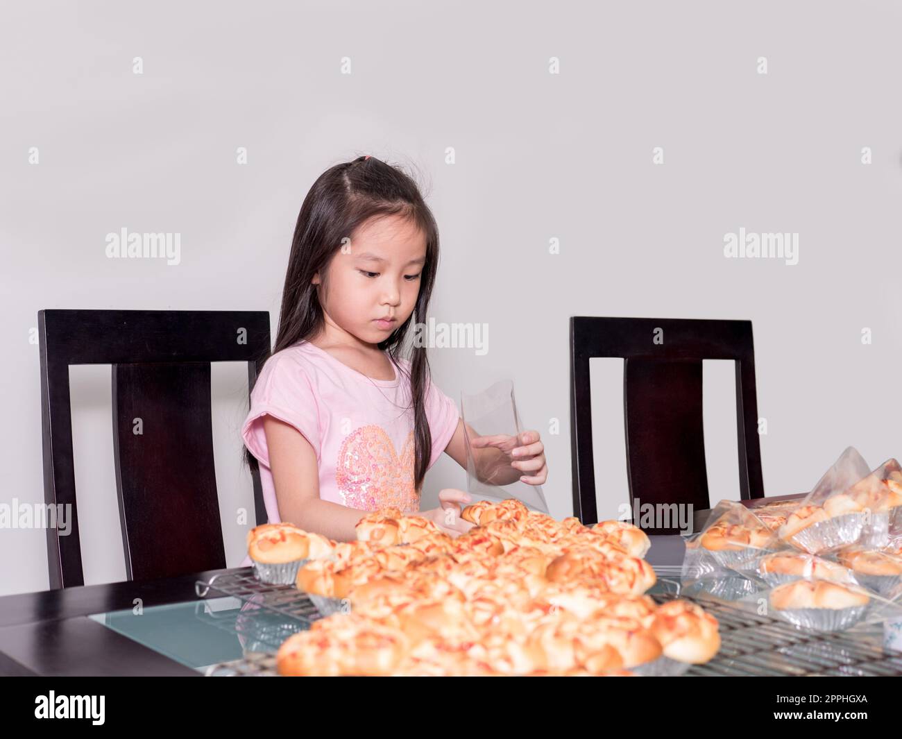 Adorable kid girl separate packing baked pork sausage with mayonnaise ...