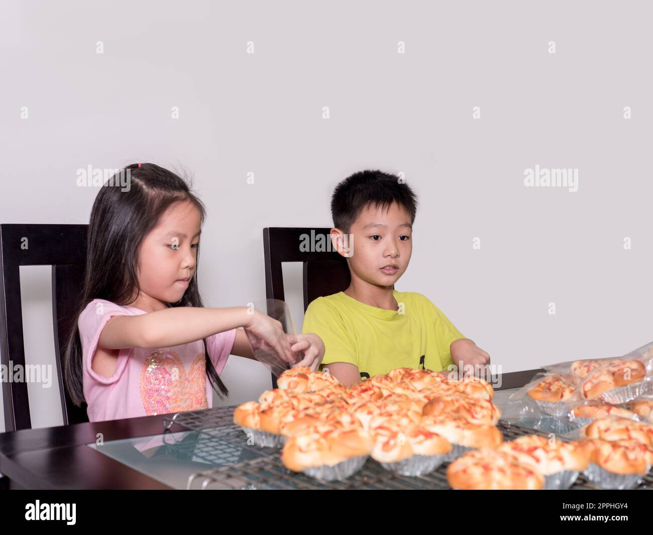 Adorable kid girl and boy separate packing baked pork sausage with ...