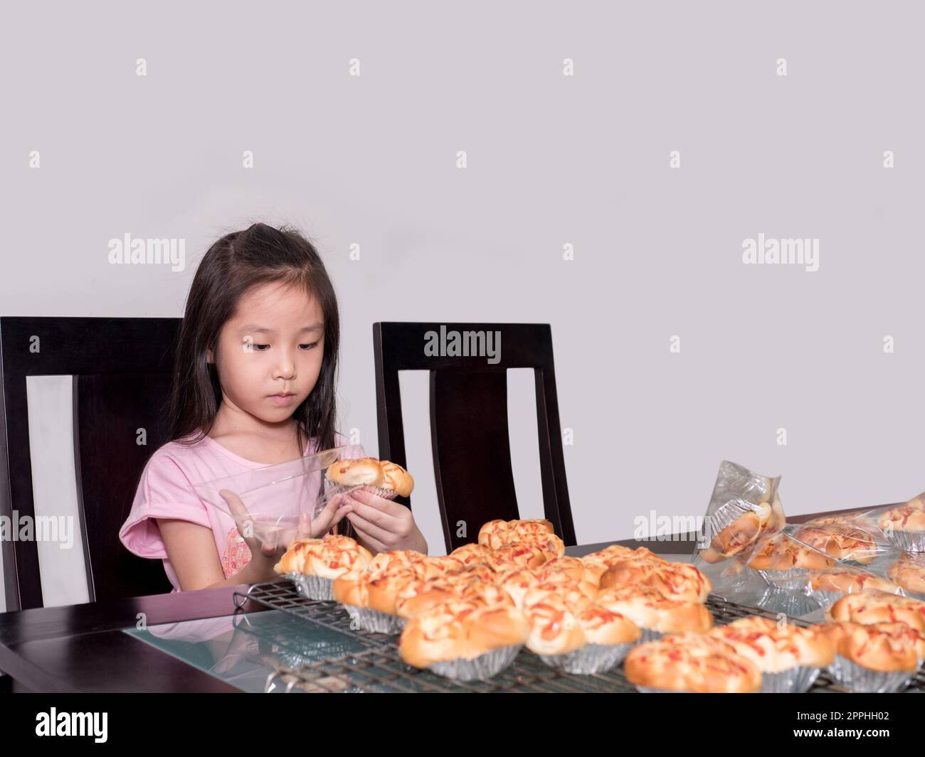 Adorable kid girl separate packing baked pork sausage with mayonnaise ...