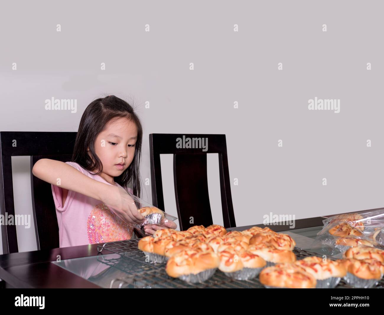 Adorable kid girl separate packing baked pork sausage with mayonnaise ...