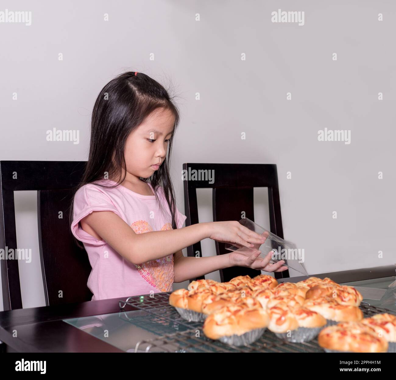 Adorable kid girl separate packing baked pork sausage with mayonnaise ...