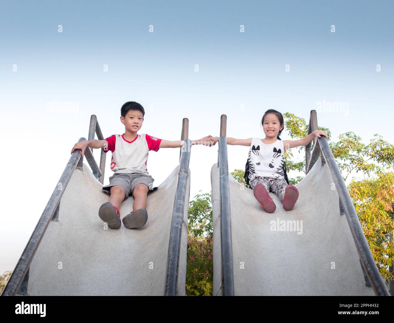 Asia pretty little girl and handsome boy play the slider in the garden ...