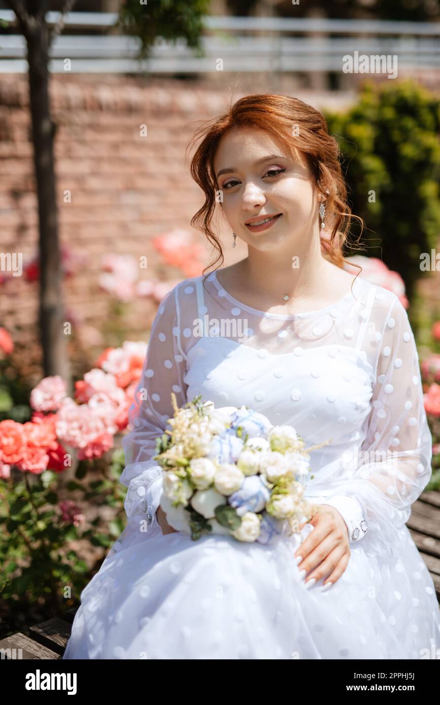 portrait of a young bride girl in a light dress in an urban environment ...