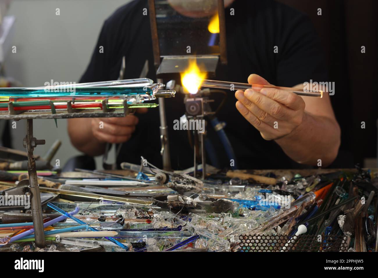 Glassworker while shaping the glass with a very high temperature flame ...
