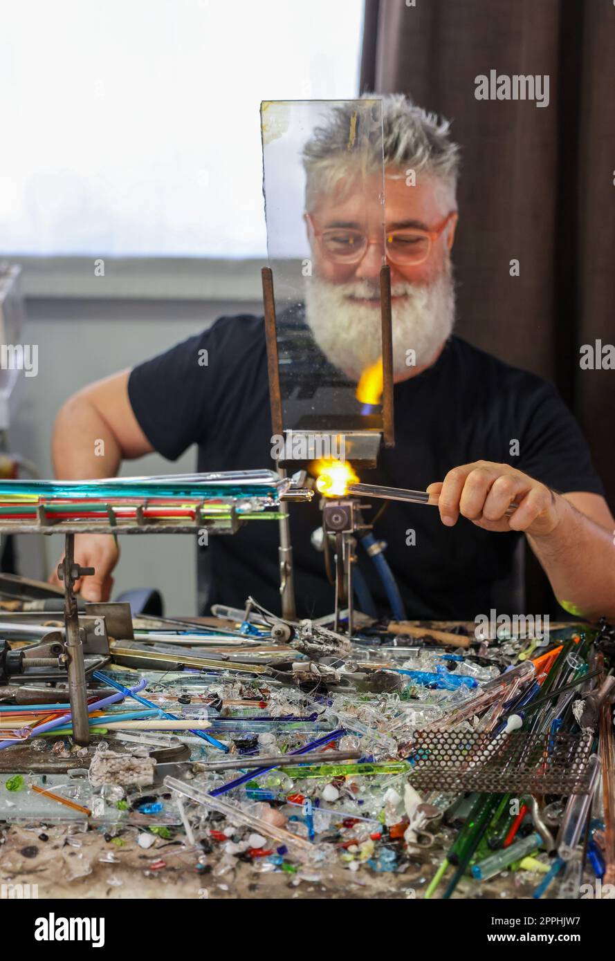 Glassworker while shaping the glass with a very high temperature flame ...