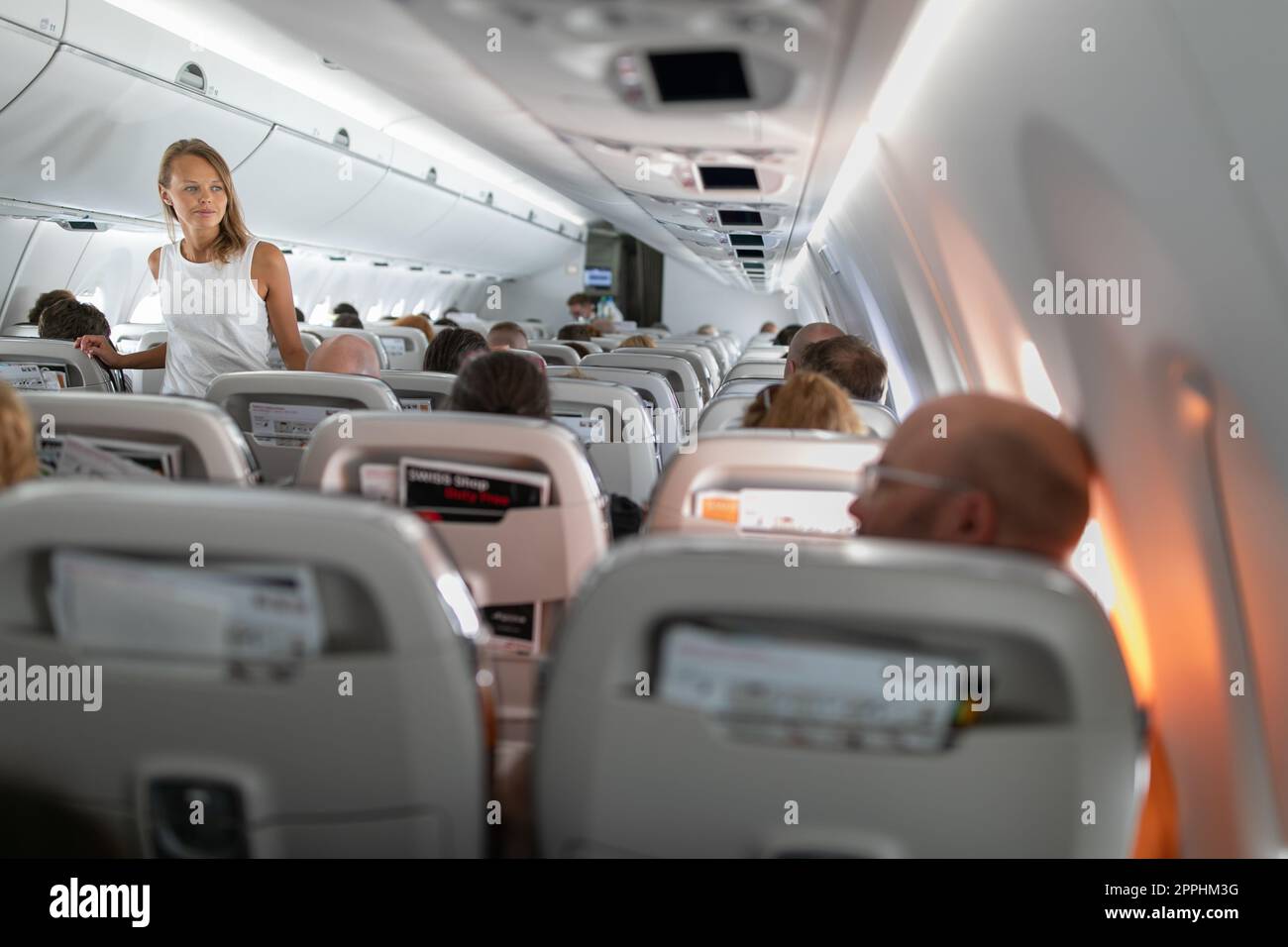 Pretty, young happy woman aboard an airplaneduring a lang haul ...