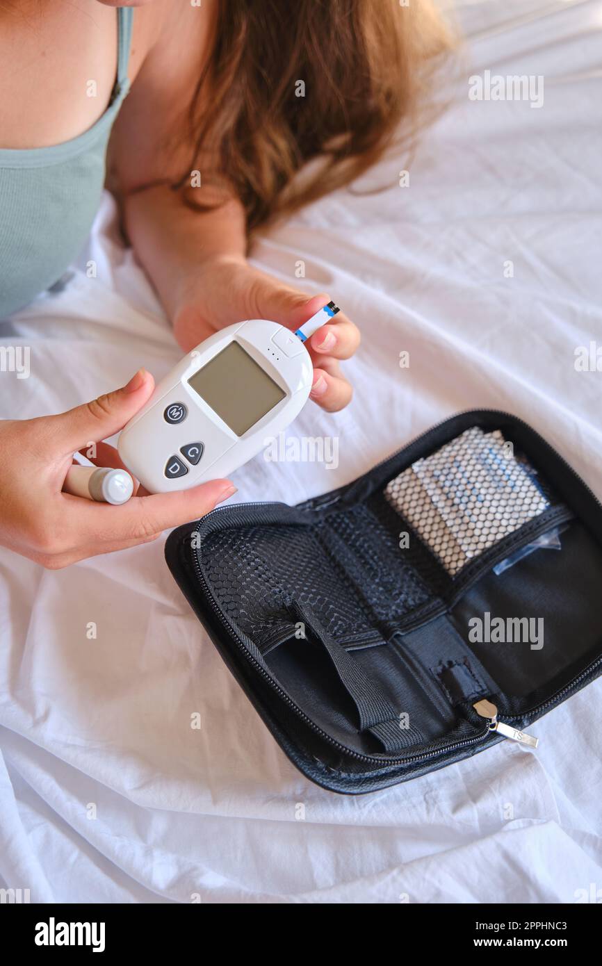 A girl inserts a test strip into a glucometer to measure blood sugar ...