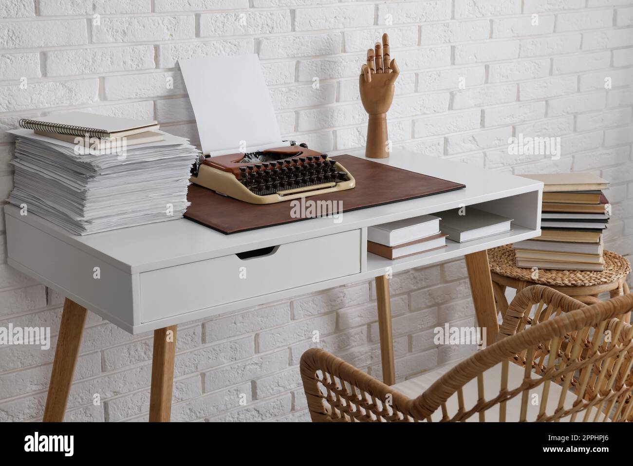 Comfortable writer's workplace with typewriter on desk near white brick ...