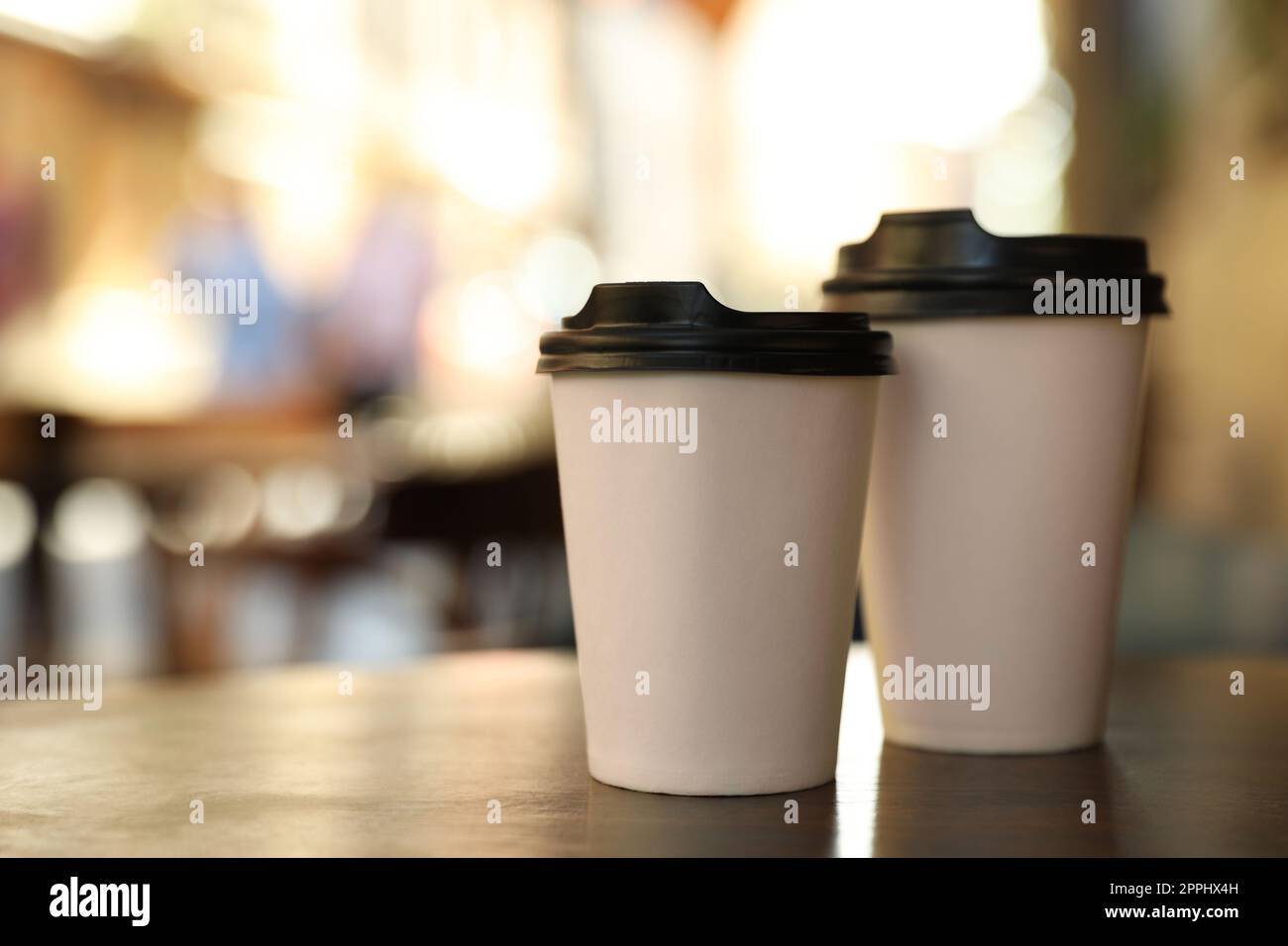 Cardboard takeaway coffee cups with plastic lids on wooden table in ...