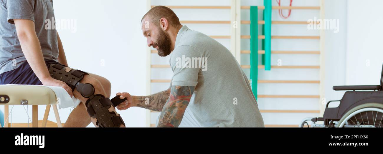 Helpful professional physiotherapist helps the patient to put on an ...