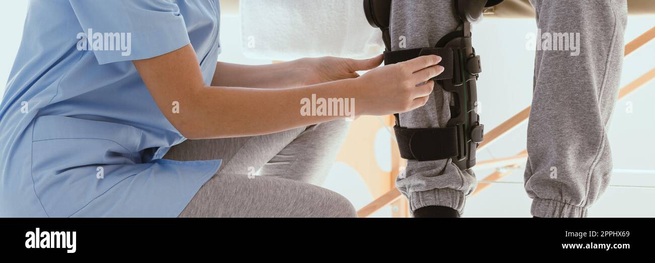 Helpful professional physiotherapist helps the patient to put on an ...