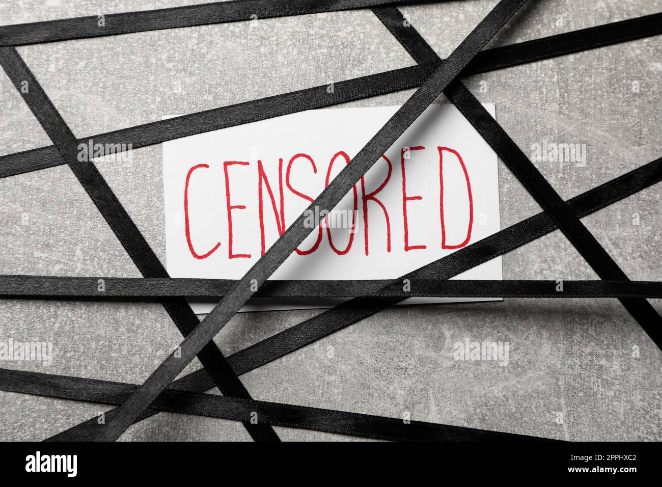 Card with word Censored and black ribbon on light grey table, flat lay ...