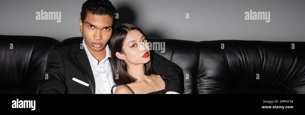 elegant african american man embracing sensual asian woman with red lips on grey background ...