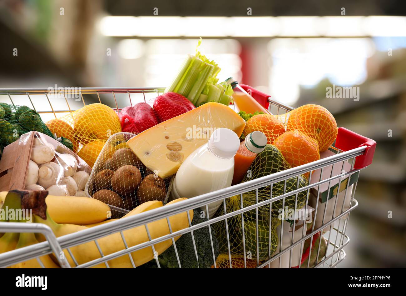 Shopping cart with different groceries in supermarket Stock Photo - Alamy
