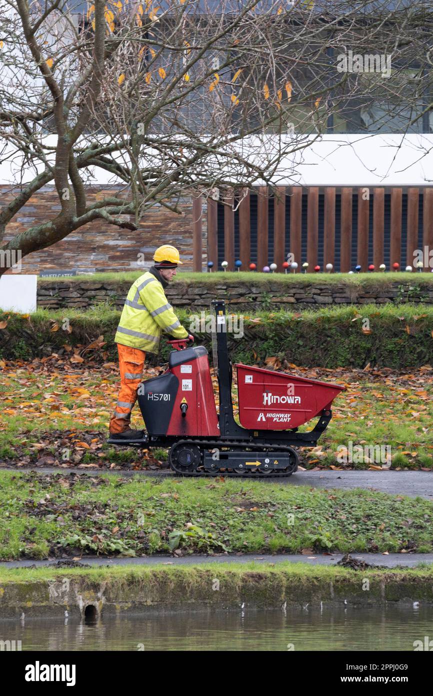 A worker operating a Hinowa Stand-on Tracked mini-dumper moving along a ...