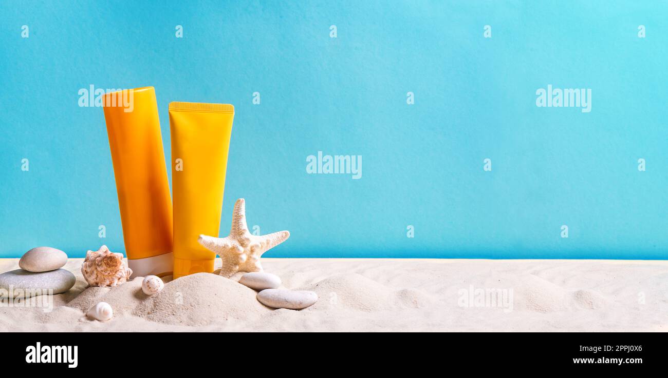 Sunblock lotion bottles, starfish, sea shells and sunglasses on blue ...