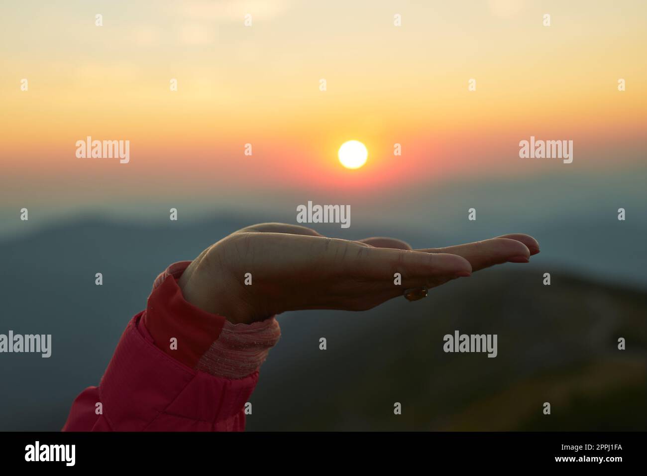 Sun over female hand. Sunrise in mountains. Ready for adventure ...
