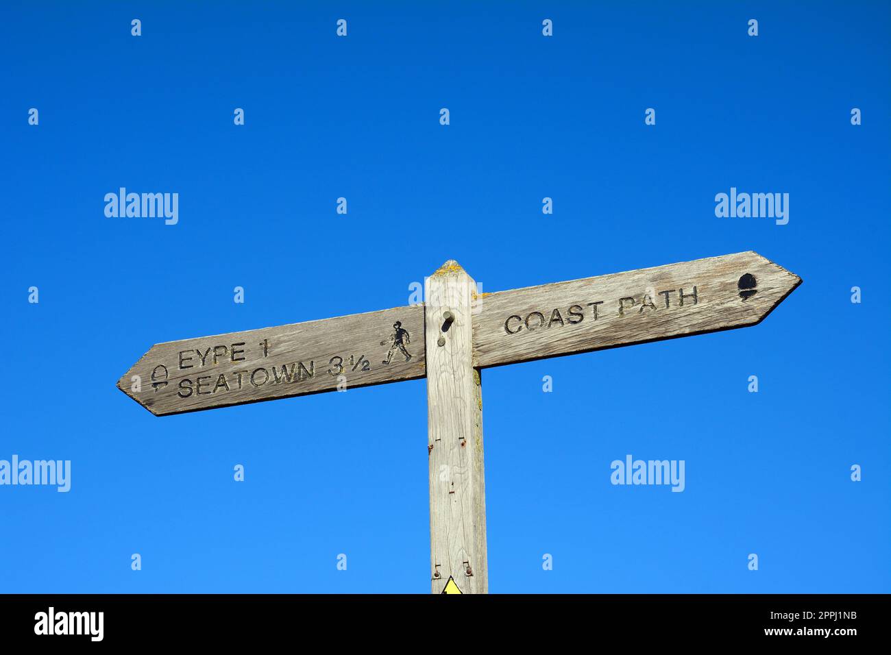 Wooden coast path sign with walking route to Eype and Seaton against a ...