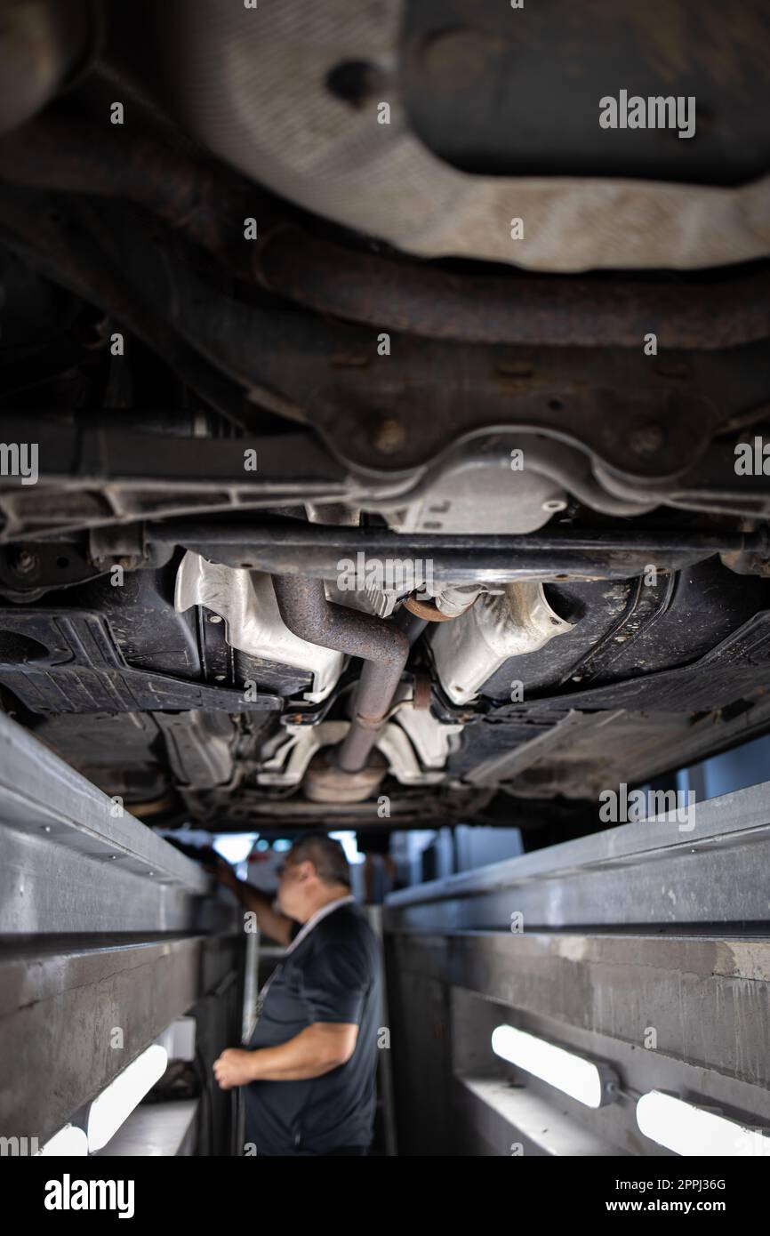 Car mechanic under a car in a repair shop/car garage (shallow DOF/color ...