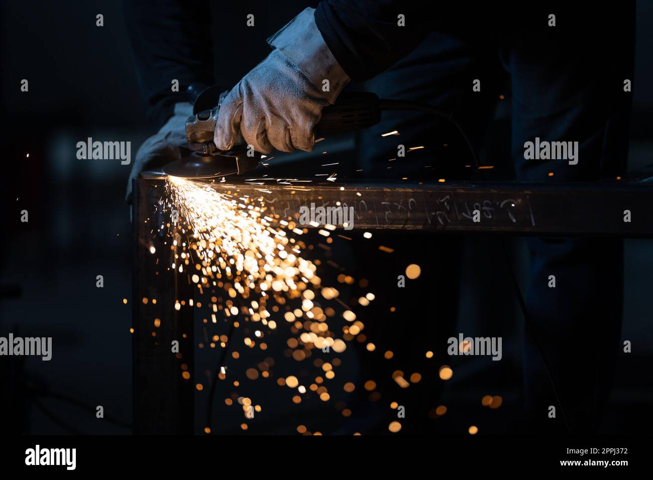 Man working on iron with grinder. Man at work. Sparkles and fire from ...