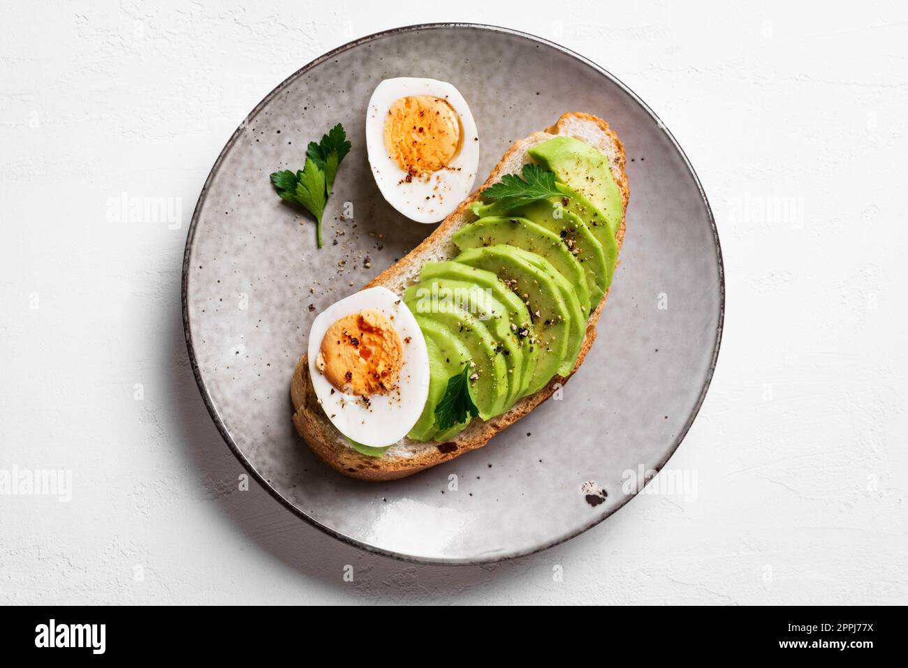 Avocado toast with boiled eggs on plate. Toasted bread with sliced ...