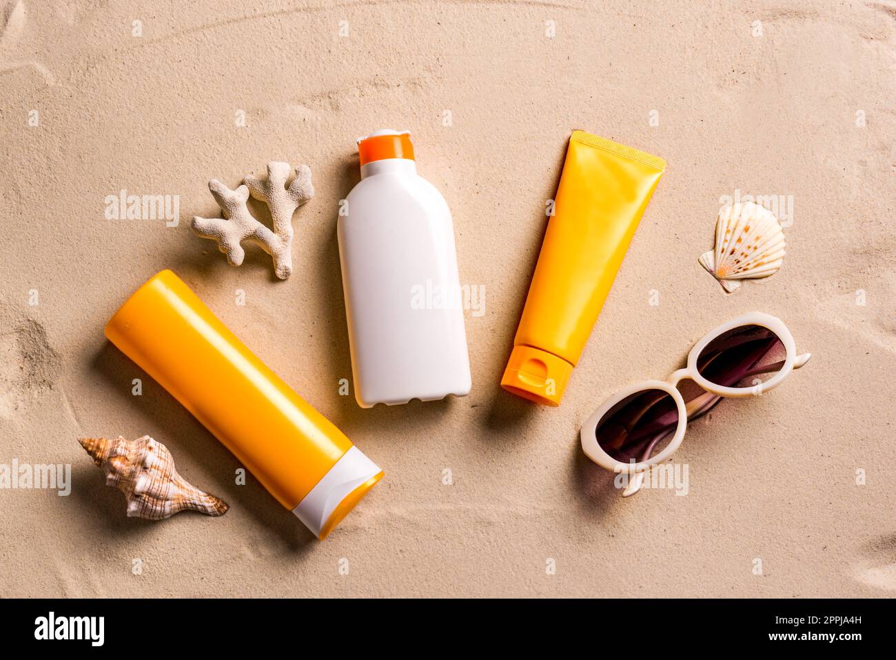 Sunblock lotion tubes and bottles and sunglasses on sandy beach background. Summer vacation and ...