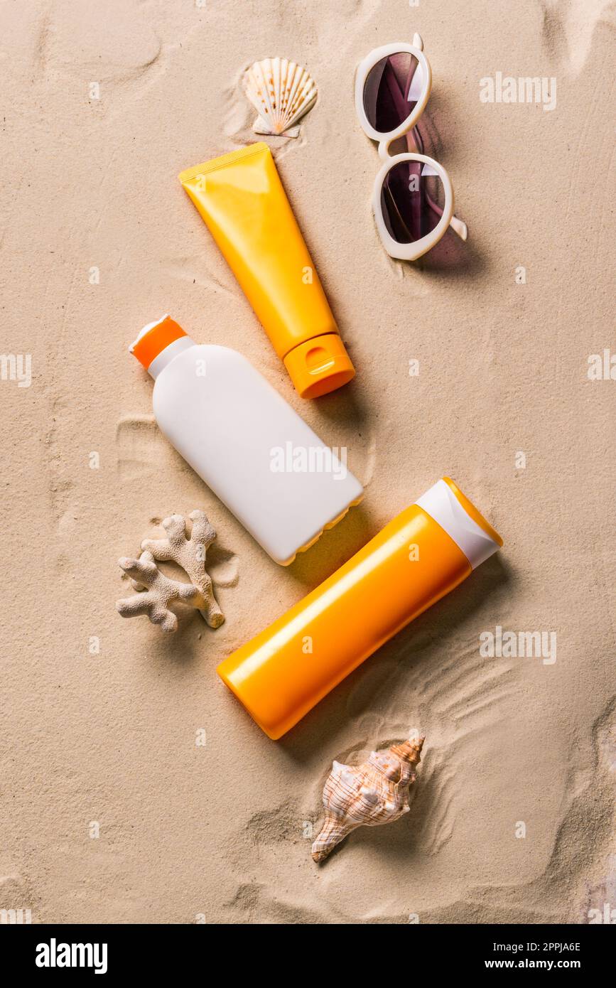 Sunblock lotion bottles, sea shell and sunglasses on sandy beach ...