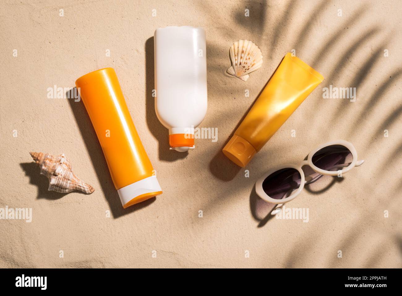 Sunblock lotion bottles, sea shell and sunglasses on sandy beach ...