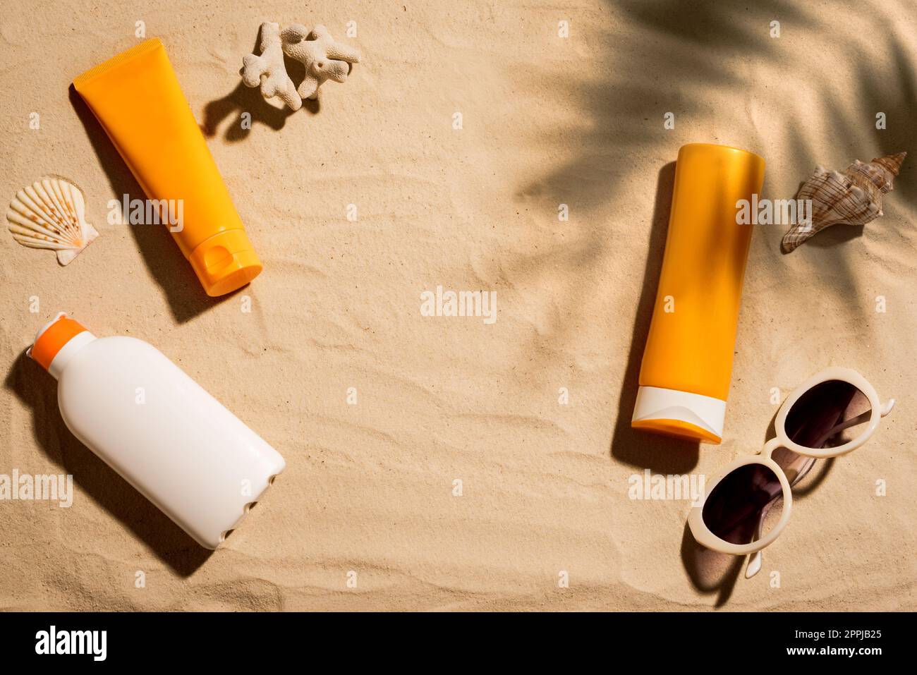 Sunblock lotion bottles, sea shells and sunglasses on sandy beach, copy ...
