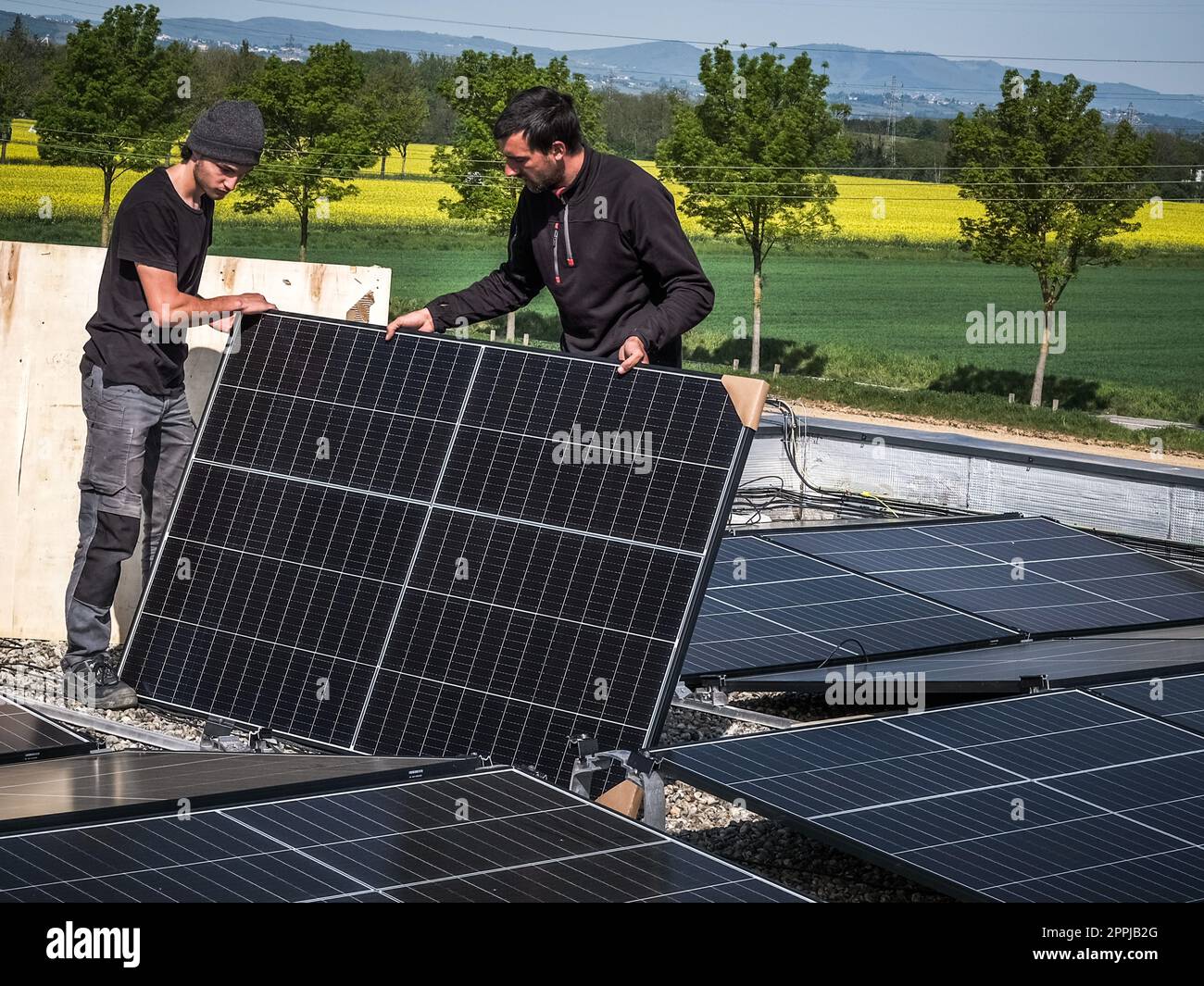Male team engineers installing stand-alone solar photovoltaic panel ...