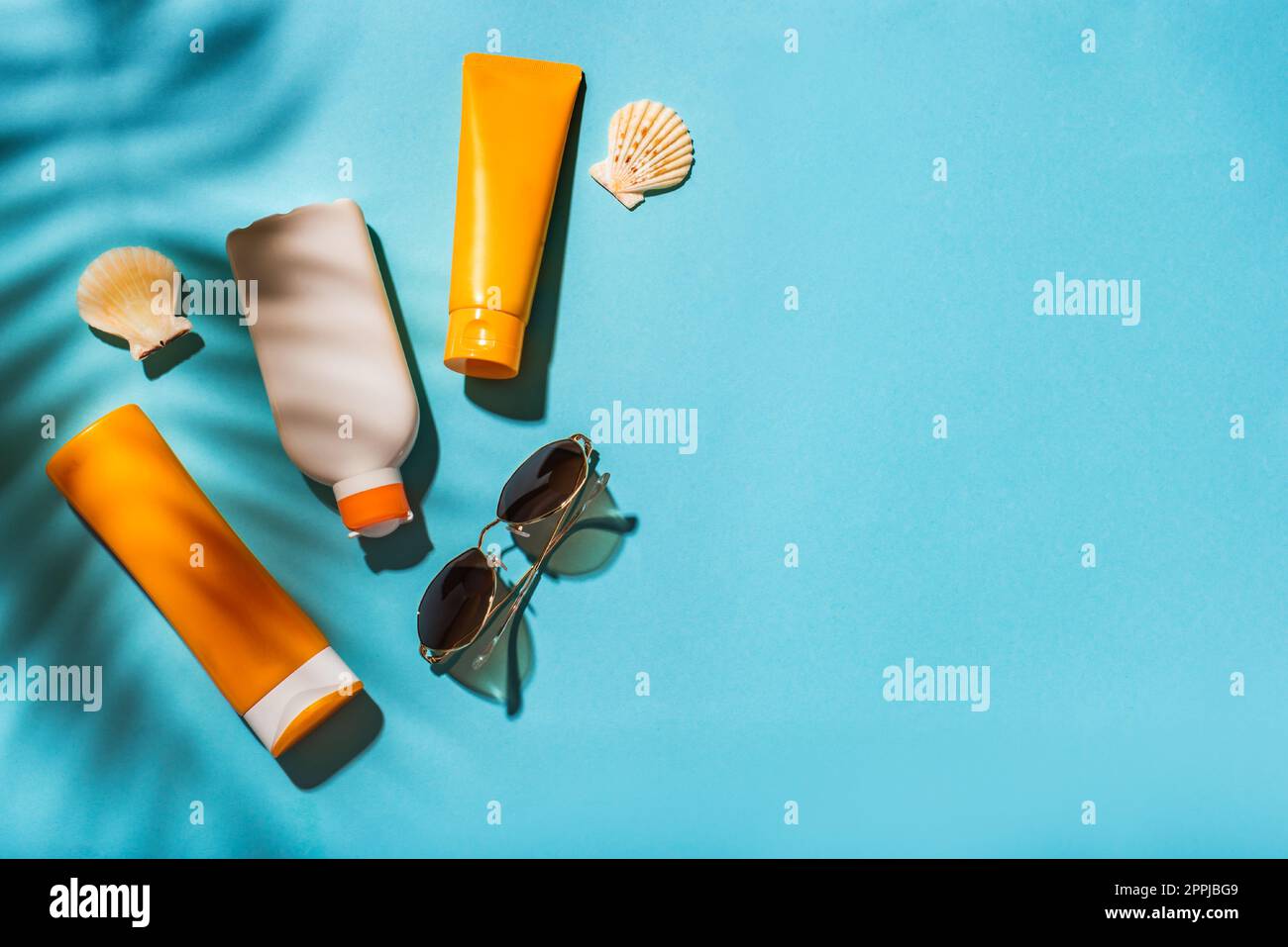 Sunblock lotion bottles, sea shells and sunglasses on blue background ...