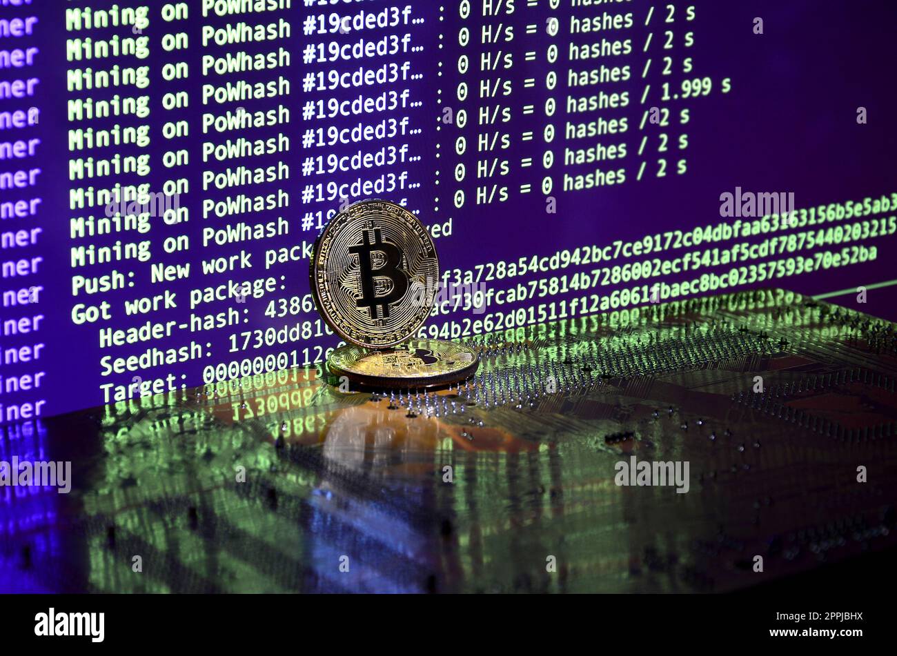 Two bitcoins lies on a videocard surface with background of screen ...