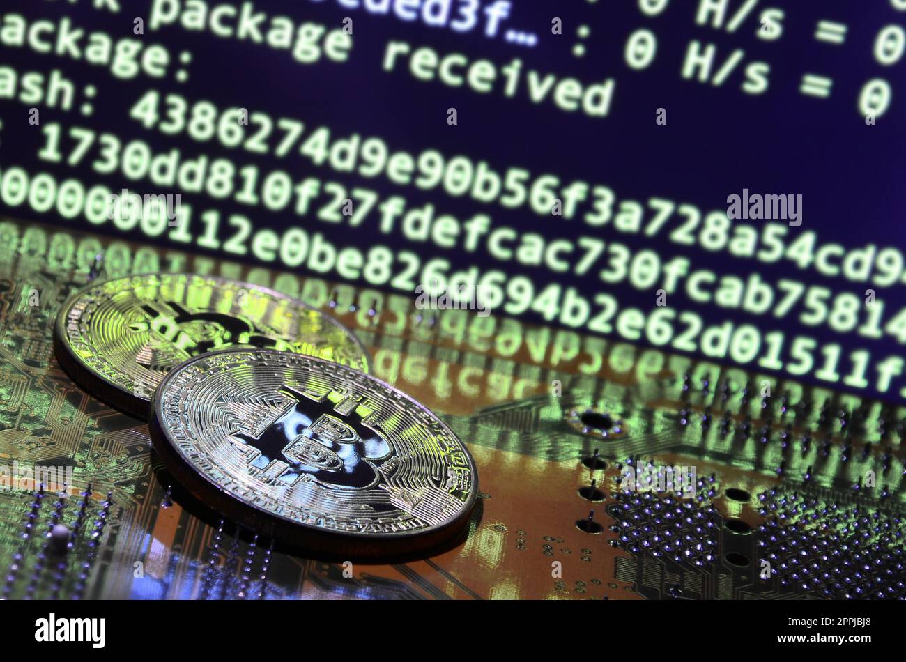 Two bitcoins lies on a videocard surface with background of screen ...
