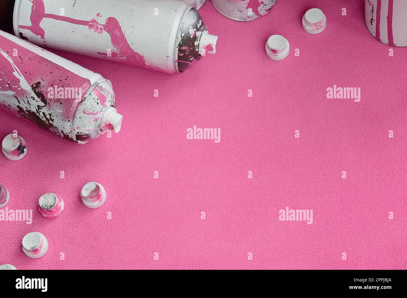 Some used pink aerosol spray cans and nozzles with paint drips lies on ...