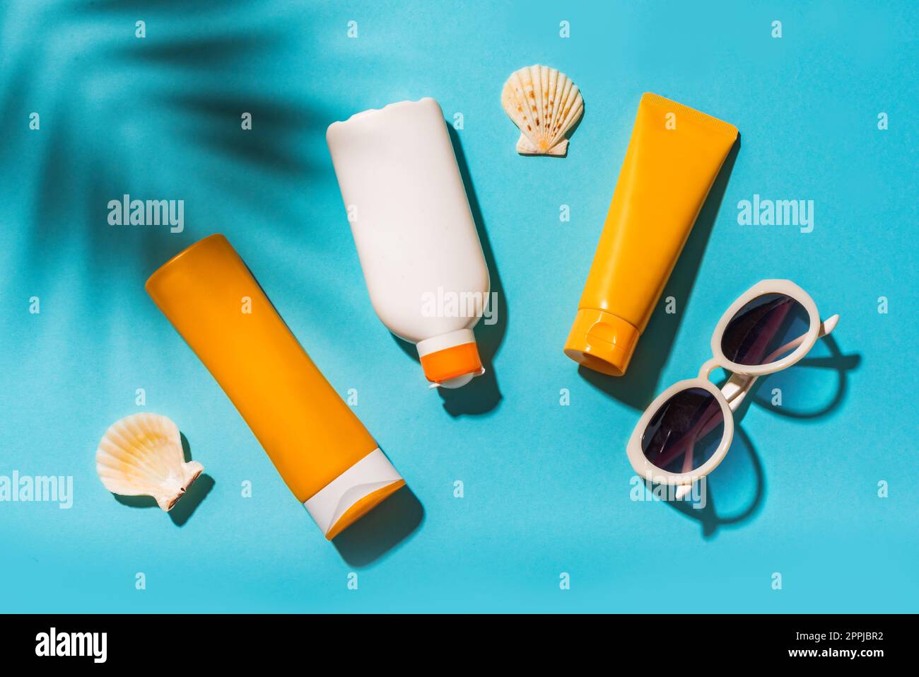 Sunblock lotion bottles, sea shells and sunglasses on blue background ...