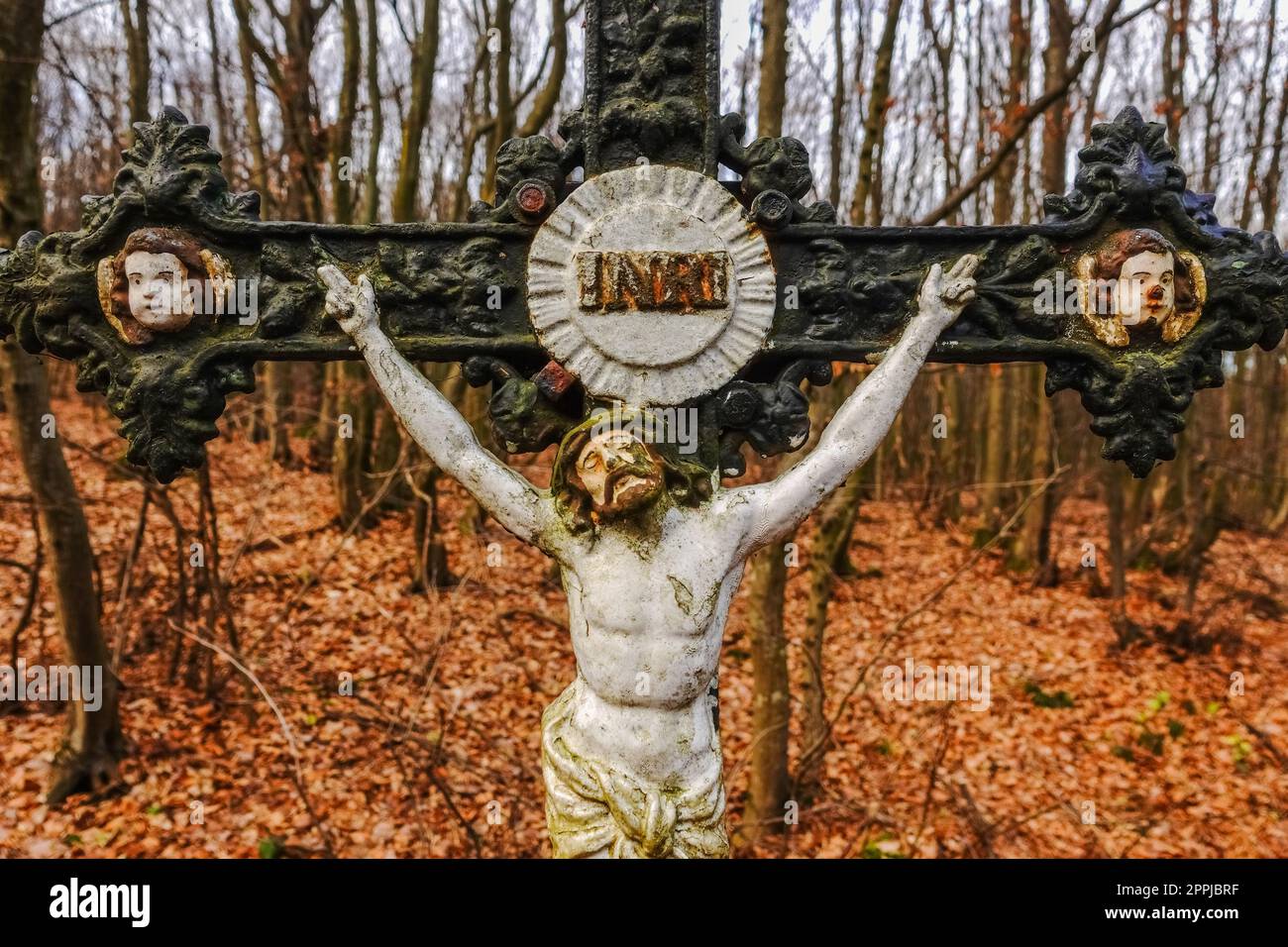 cross with jesus at a place in the forest detail Stock Photo - Alamy