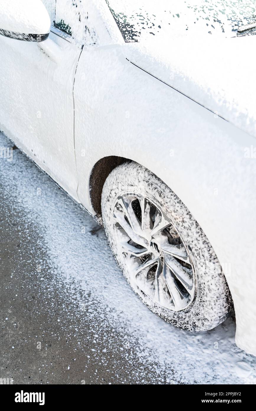Hand washing with high pressure water in a car wash outside. The car is ...