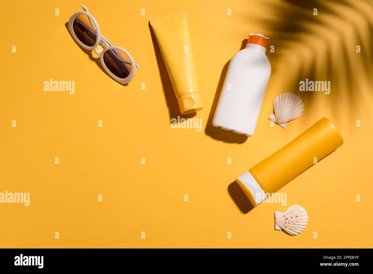 Sunblock lotion bottles and sunglasses on yellow background, copy space ...