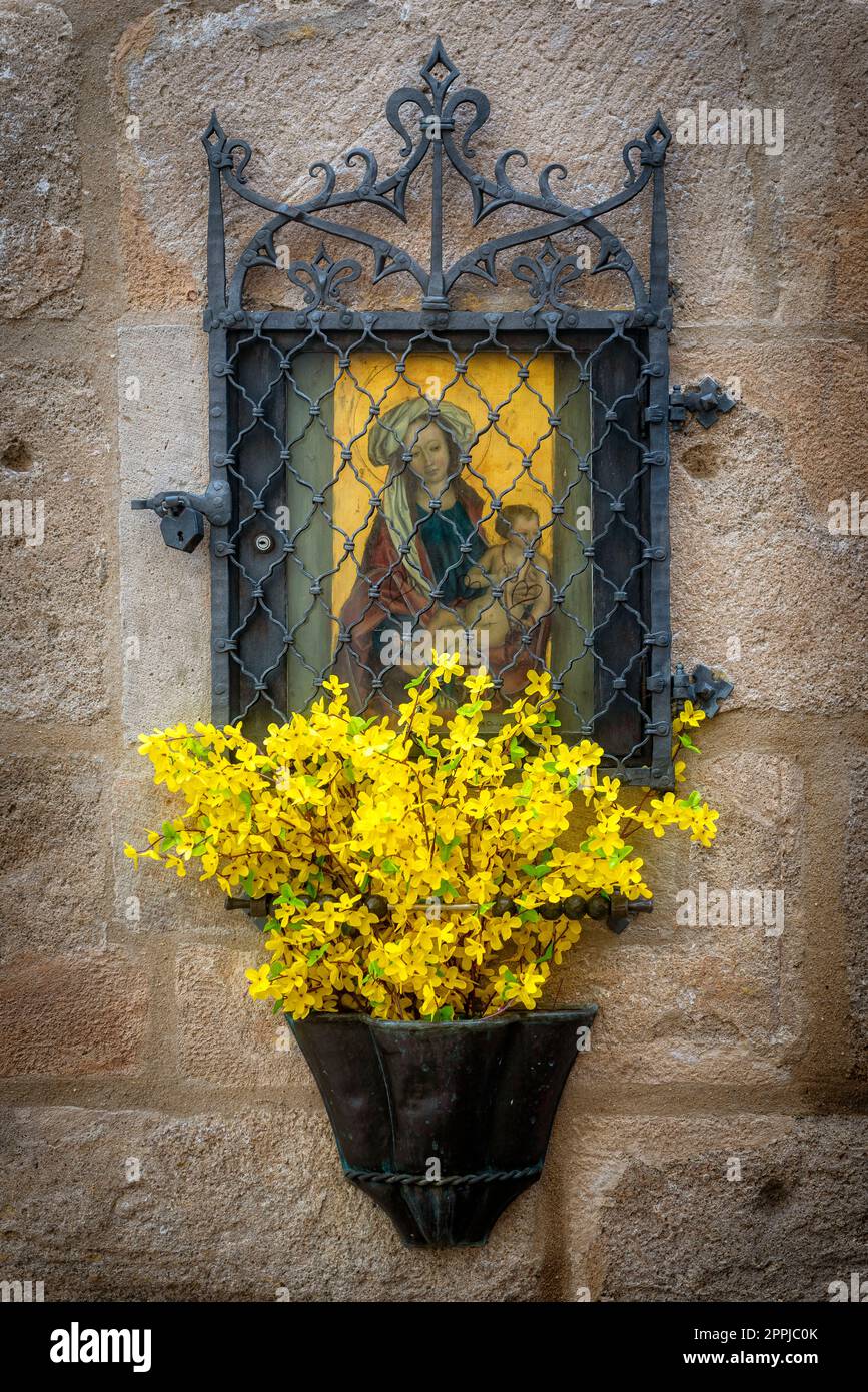 A painting of Mary and Jesus behind a grate with flowers in the ...