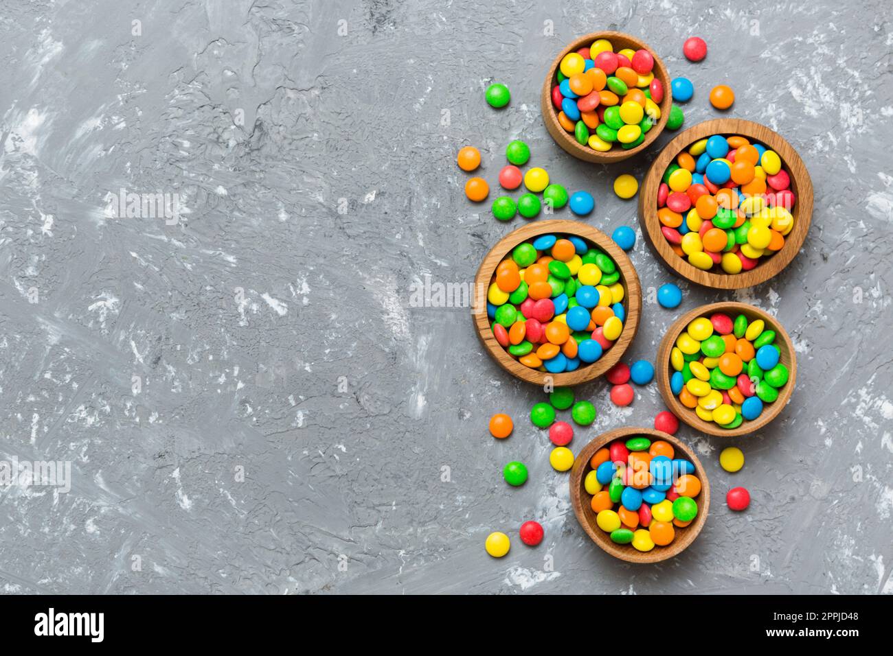 different colored round candy in bowl and jars. Top view of large ...
