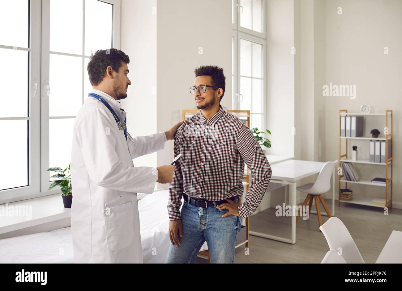 Male doctor touches patient's shoulder for encouragement and support ...