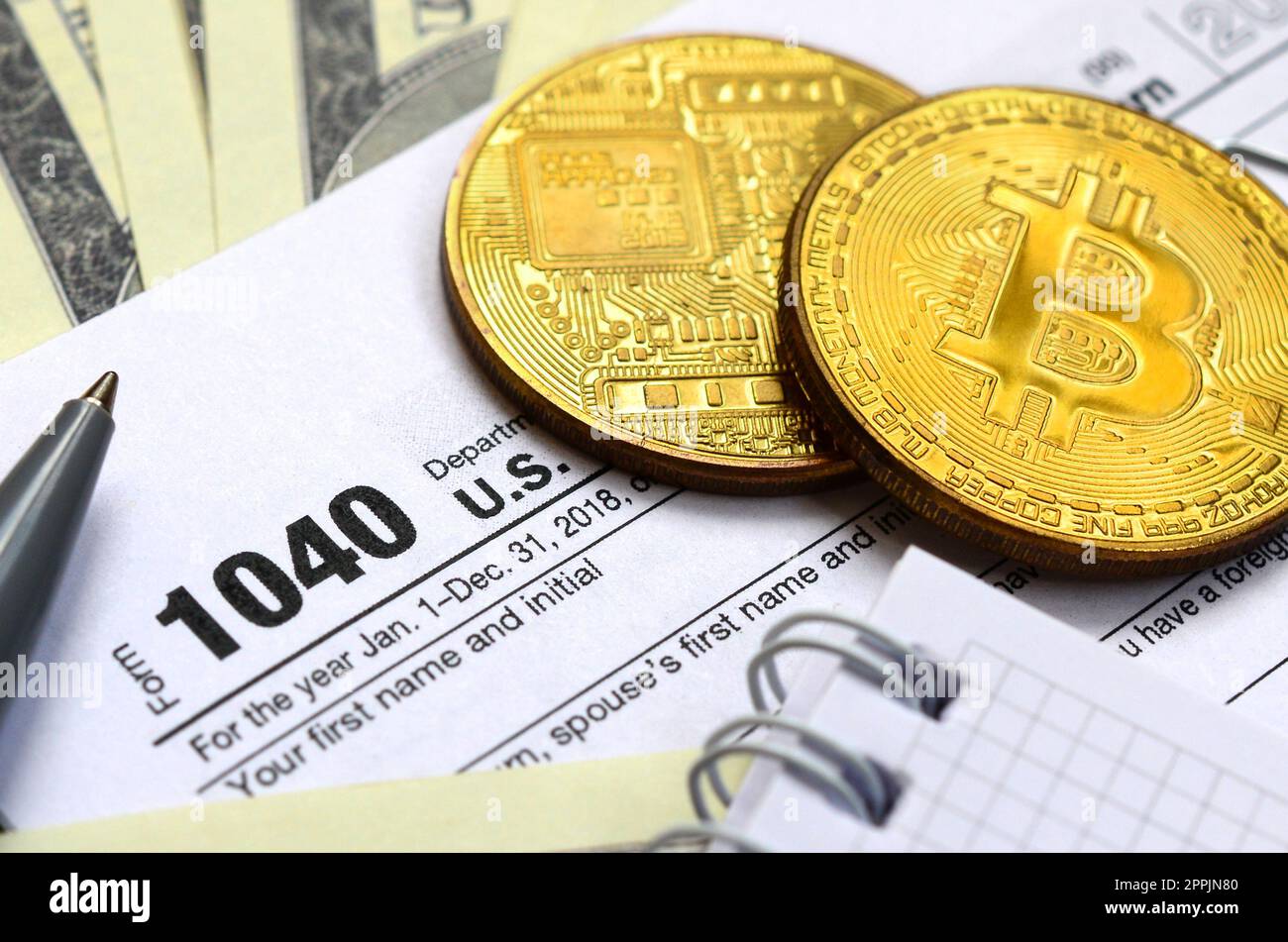 The pen, bitcoins and dollar bills is lies on the tax form 1040 U.S ...
