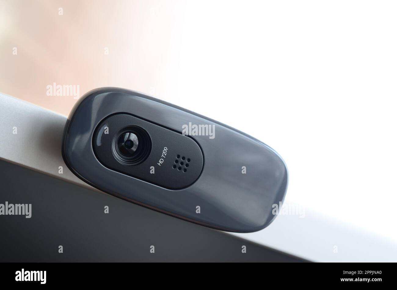 A modern web camera is installed on the body of a flat screen monitor ...