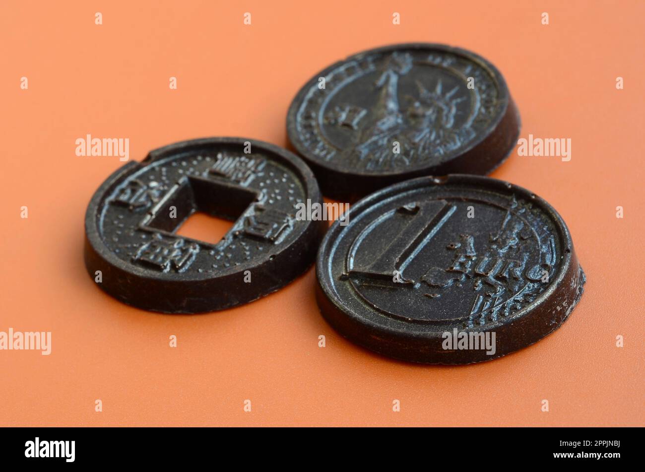 Three chocolate products in the form of Euro, USA and Japan coins lie ...