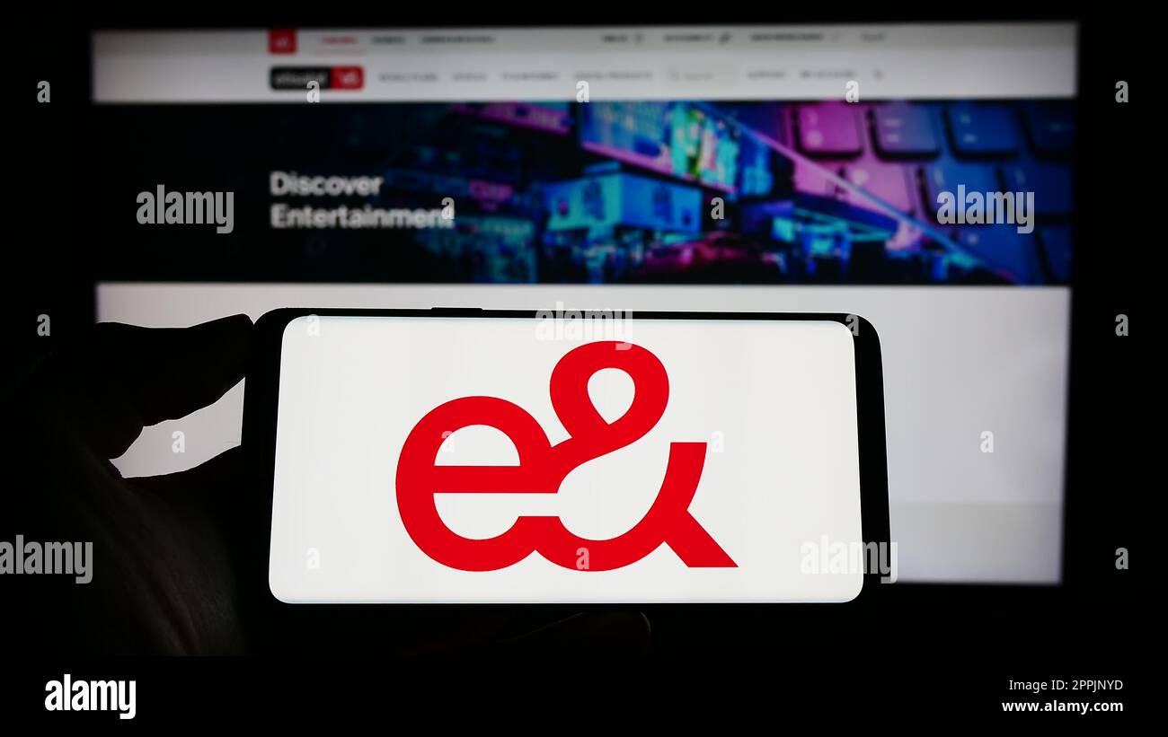 Person holding smartphone with logo of Emirates Telecommunications ...